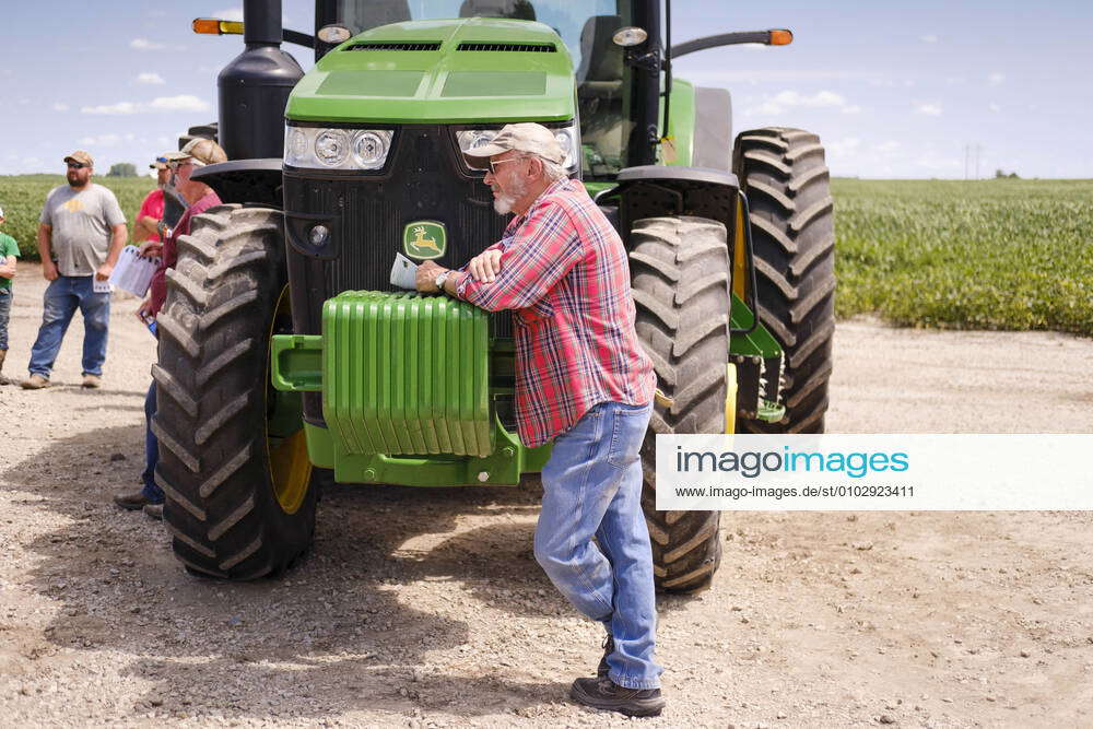 Fairfield, Iowa, U.S: A man leans against a John Deere tractor during ...